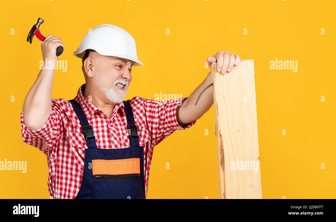 busy old man woodworker in helmet on yellow background Stock Photo - Alamy