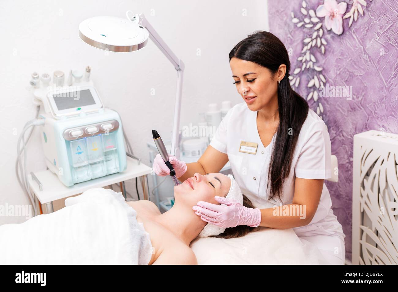 Beauty salon. Smiling cosmetologist in rubber gloves makes fractional ...