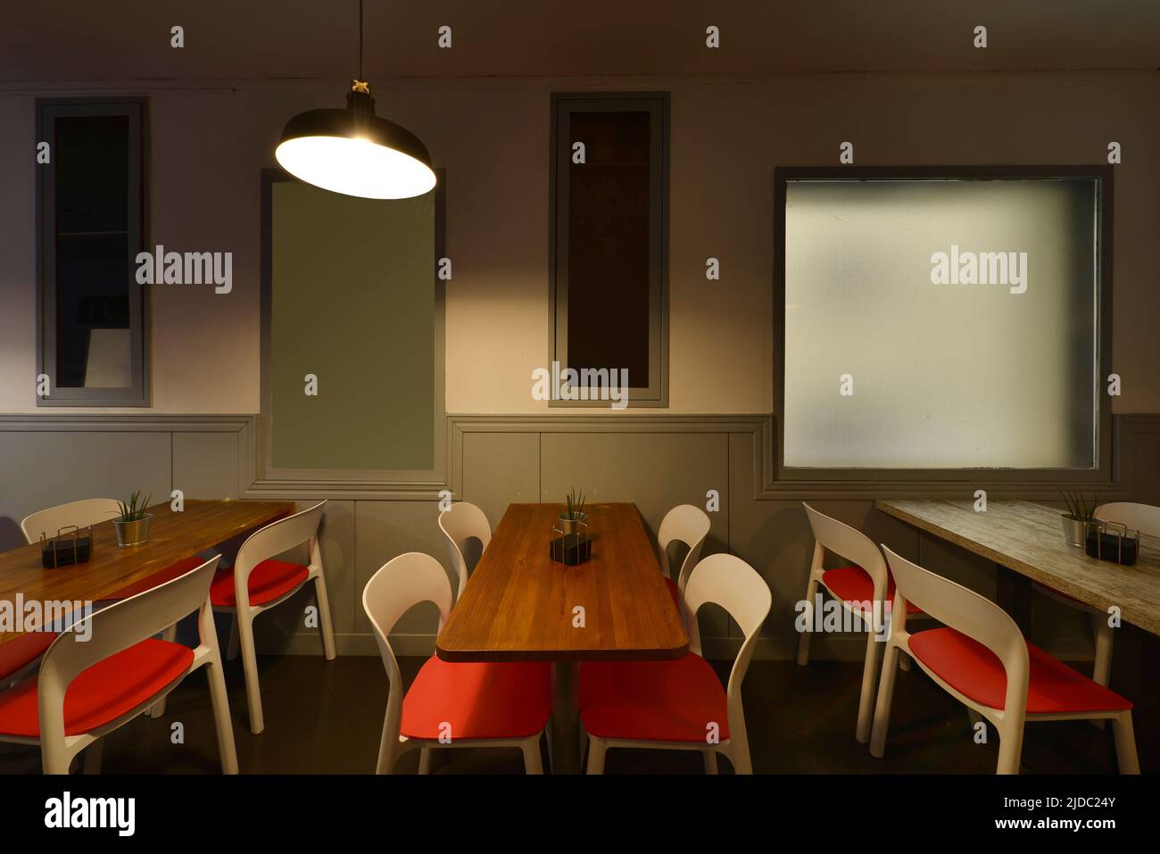 Restaurant dining room with rectangular wooden tables and white chairs ...