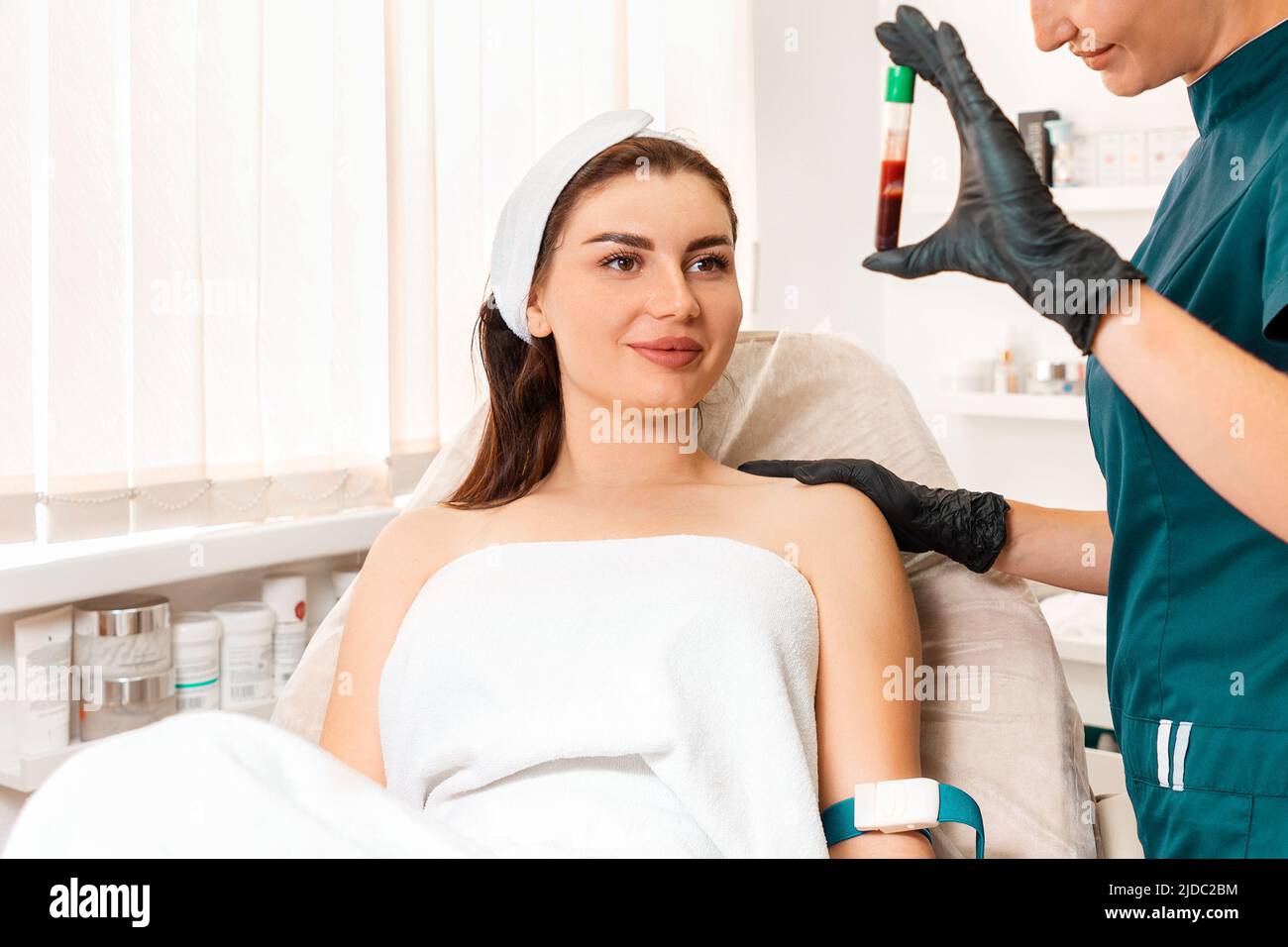 Plasmolifting. Cosmetologist shows a tube with blood to the client ...