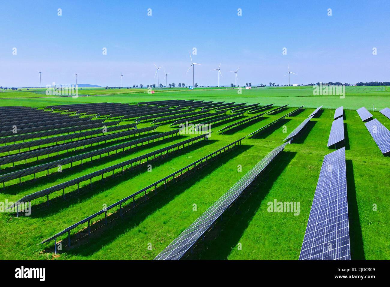 Solar panels battery in green field against blue sky, aerial view ...