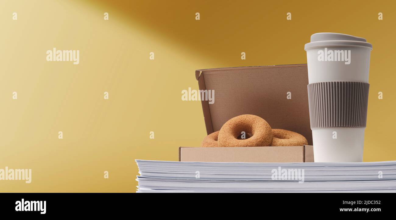 Delicious donuts and take away coffee on a pile of paperwork, it's ...
