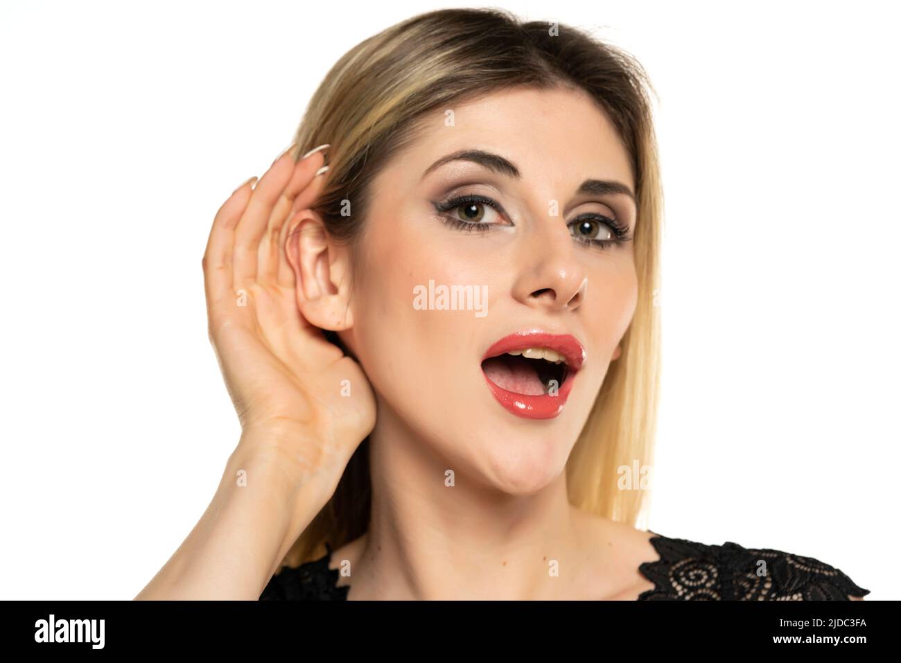 Young blond woman is straining a hand behind her ear while listening on ...