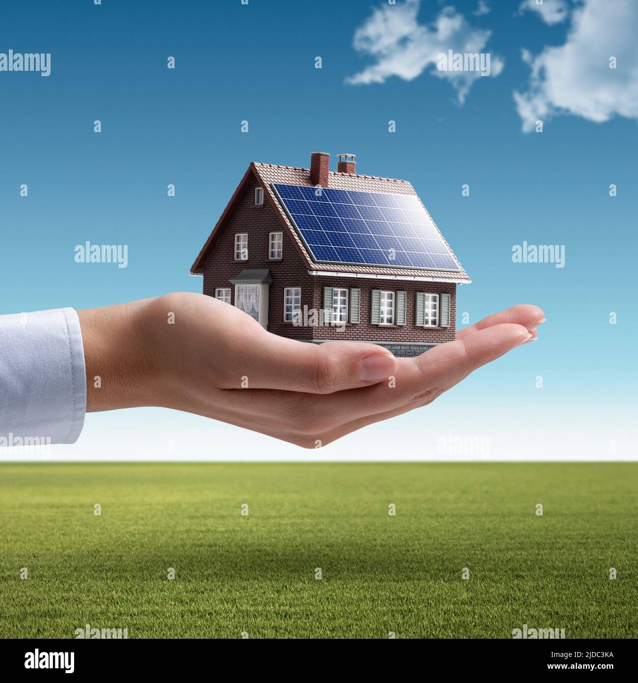 Hand holding an energy efficient model house with solar panels, ecology ...