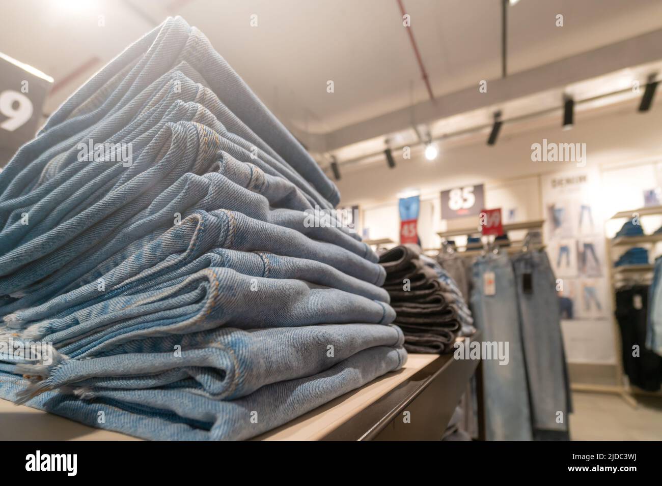 Stacks of jeans on a shelf in a mall store. Concept of buying, selling ...