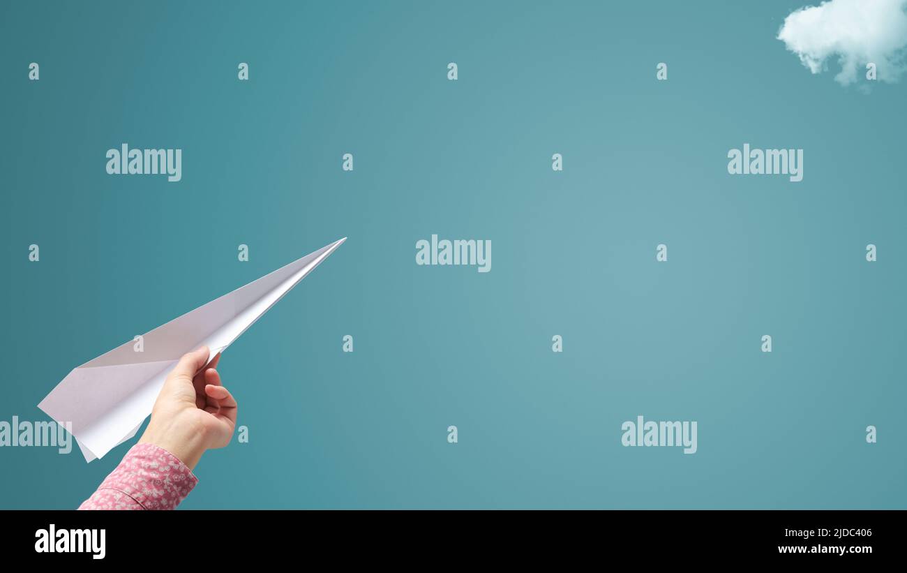 Woman holding a paper airplane and blue sky in the background ...