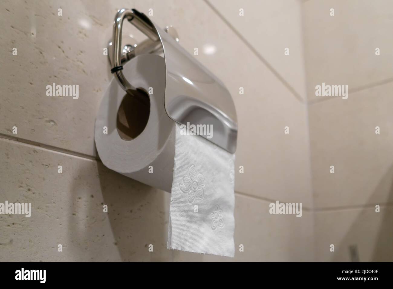 Close-up of a roll of toilet paper hanging on a light wall in the ...