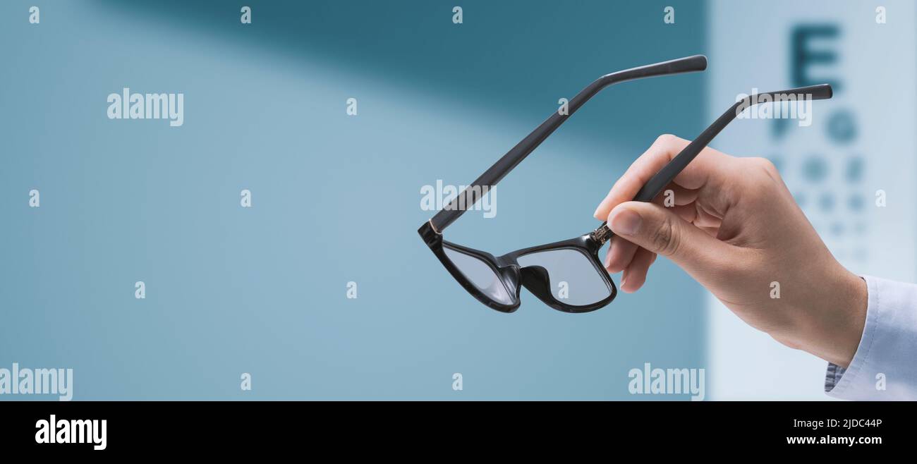 Professional optometrist holding glasses and eye chart in the ...