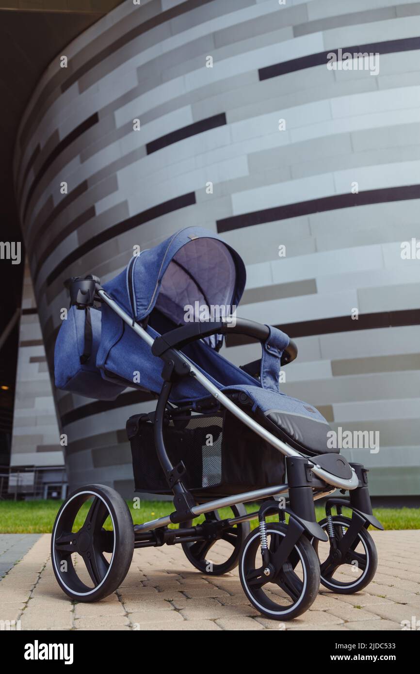 Modern contemporary blue baby stroller with long hood outdoors side ...