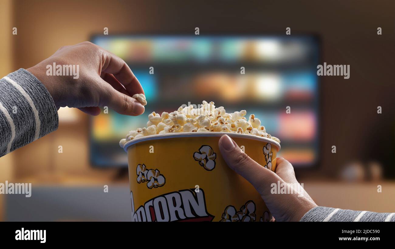 Woman eating popcorn and watching videos on demand at home on TV Stock ...