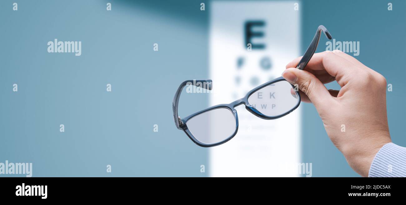 Professional optometrist holding glasses and eye chart in the ...