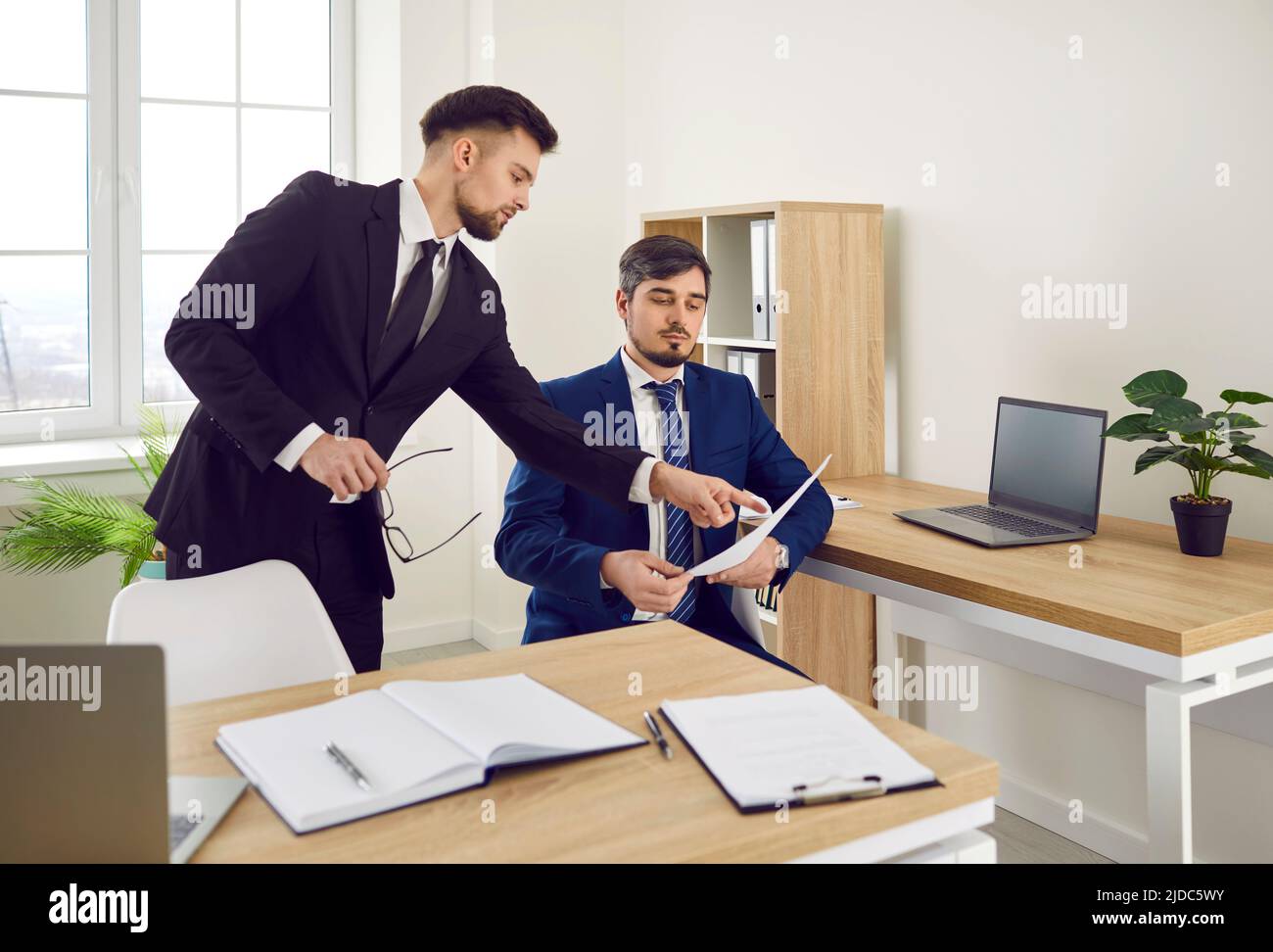 Two male business colleagues reviewing paper documents working in ...