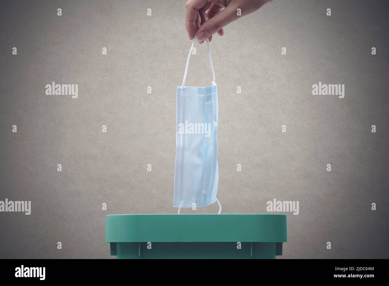 Woman putting an used face mask in the trash bin, medical waste ...
