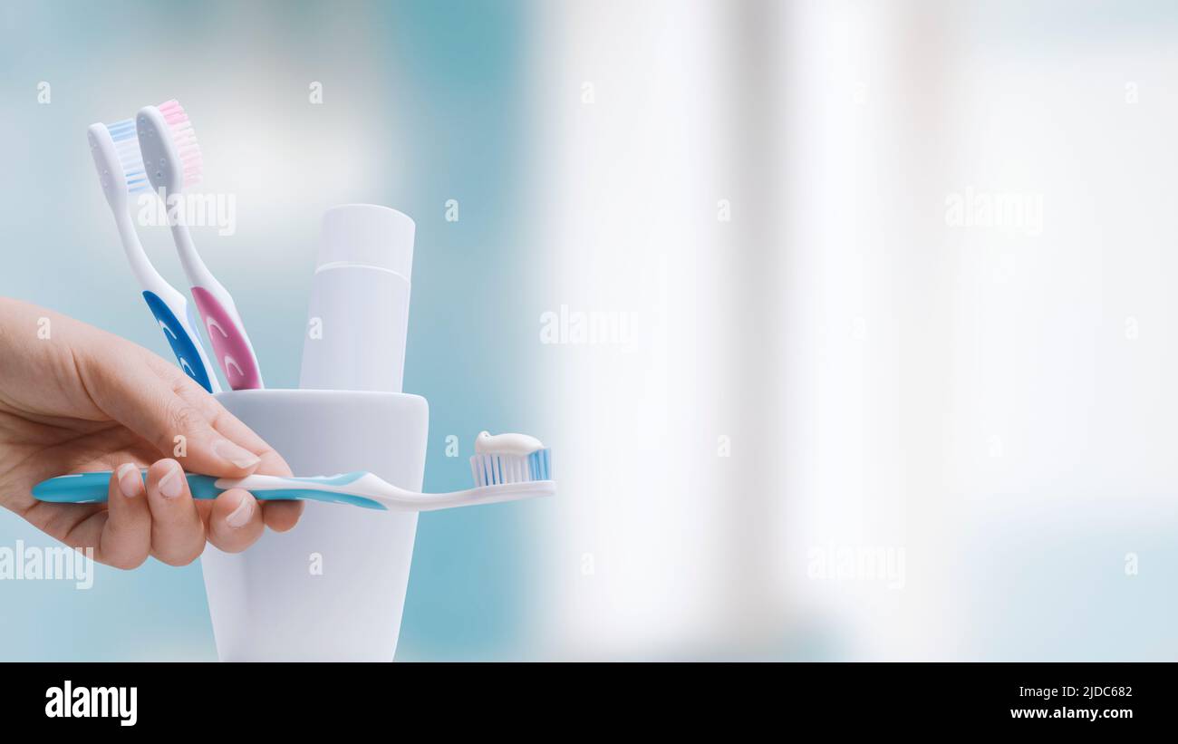 Woman holding a toothbrush with toothpaste, she is cleaning her teeth ...