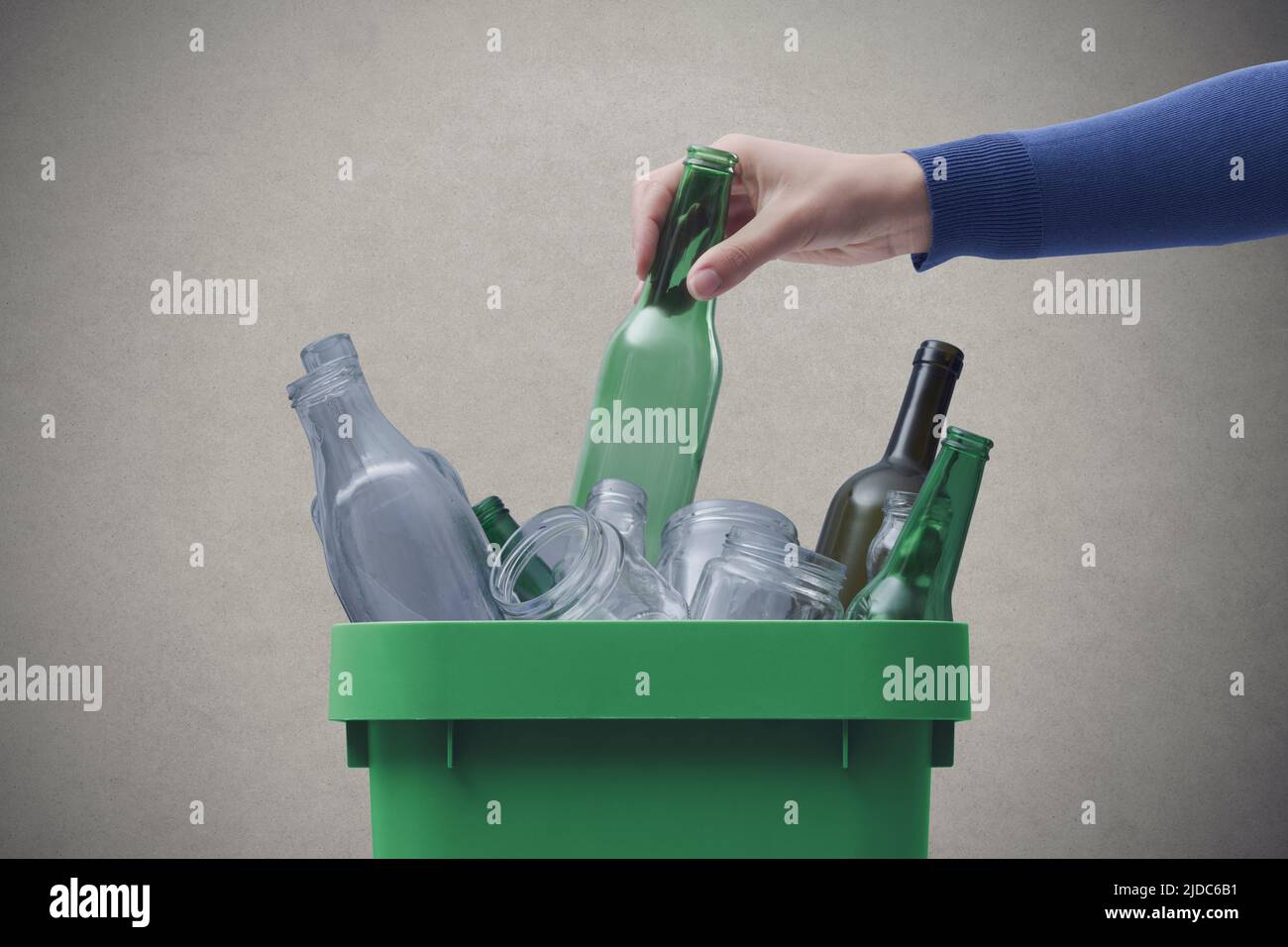 Woman putting a glass bottle in the trash bin, separate waste ...