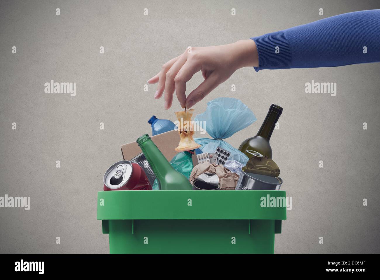 Woman putting food leftovers in undifferentiated waste bin, improper ...