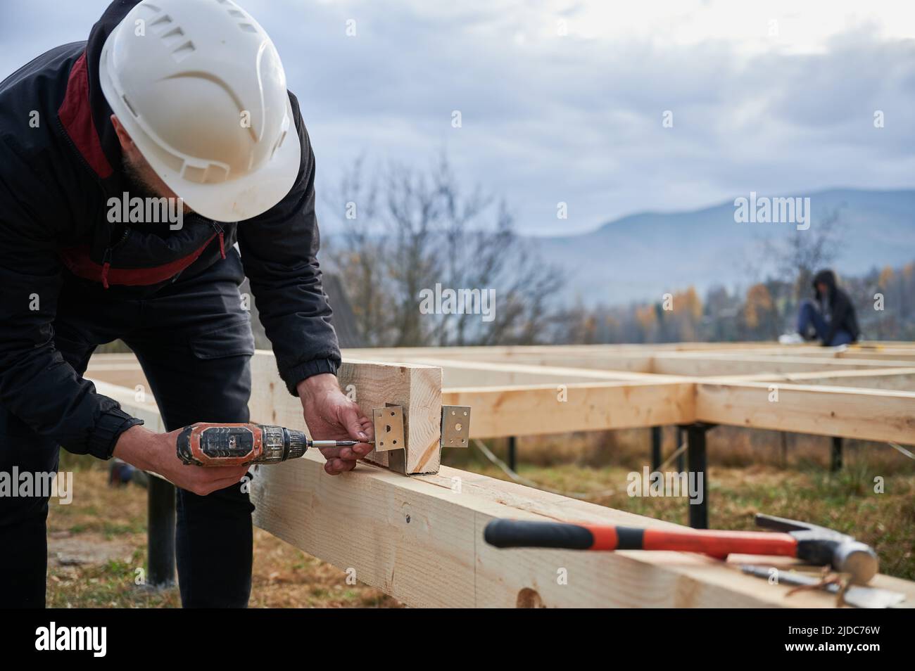 Man worker building wooden frame house on pile foundation. Carpenter ...