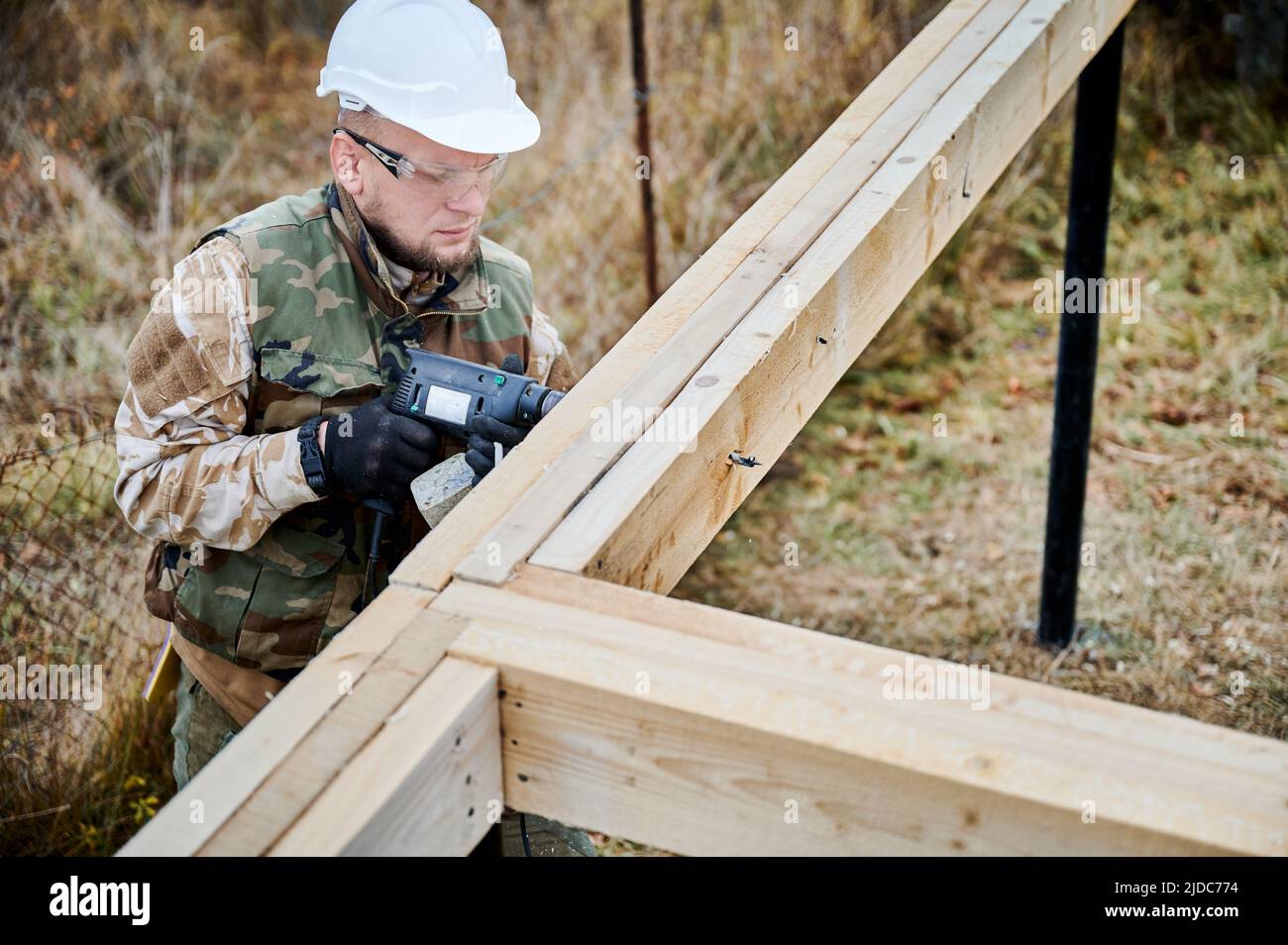 Man building wooden frame house on pile foundation. Male worker ...