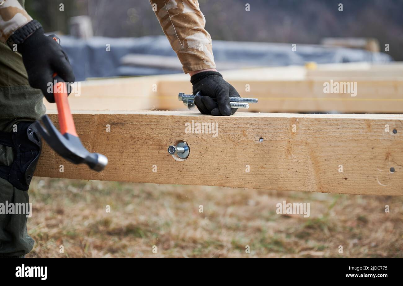 Man worker building wooden frame house on pile foundation. Carpenter ...