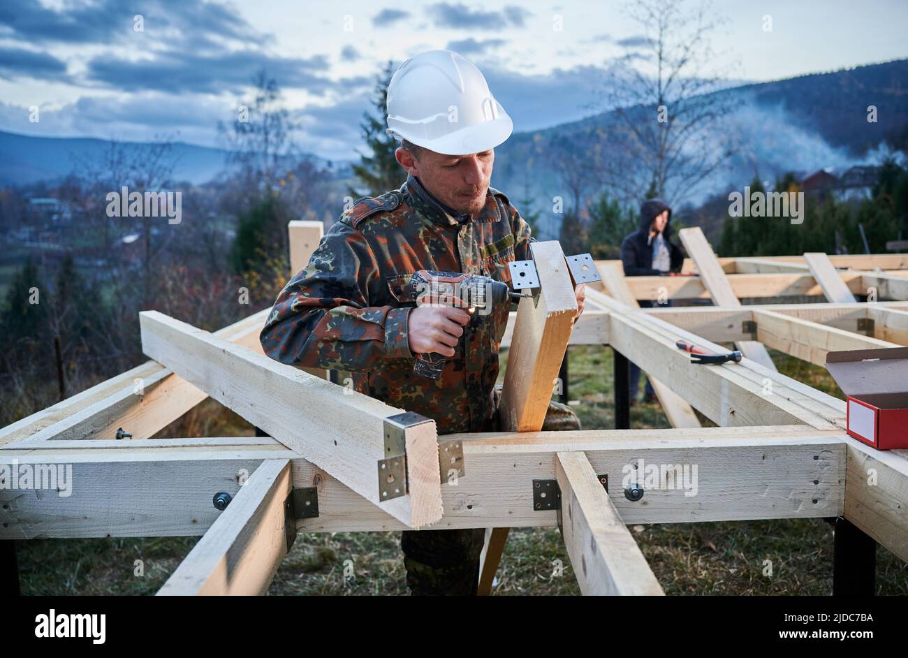 Man worker building wooden frame house on pile foundation. Carpenter ...