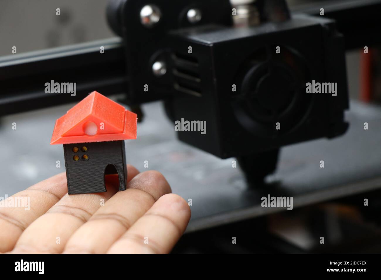 3D printed model house with a real 3d printer machine on its background ...