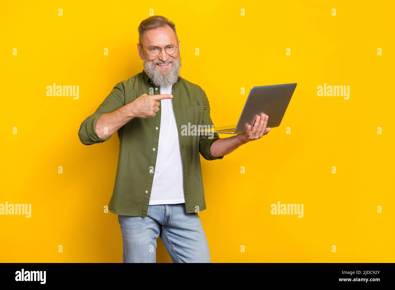 Portrait of cheerful aged man direct finger arm hold wireless netbook ...