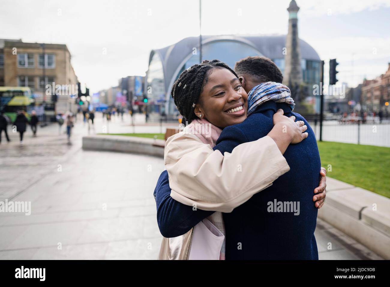Couple embracing in town, woman smiling with arms around man Stock ...