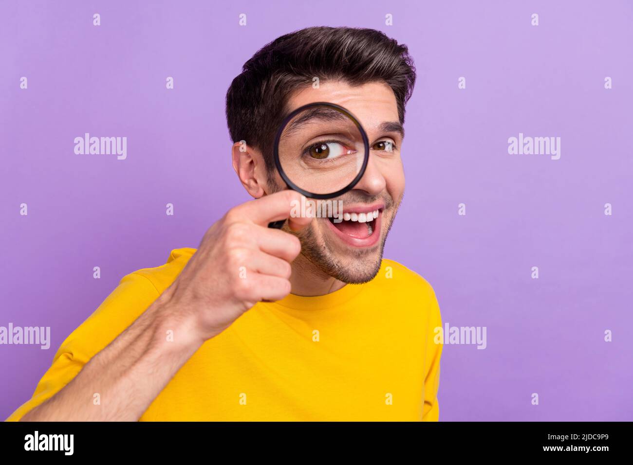 Portrait of cheerful laughing man using magnifying glass find ...