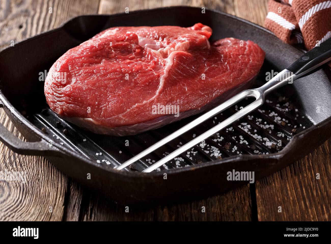 Raw piece of meat for grilling with vegetables in a cast iron pan ...