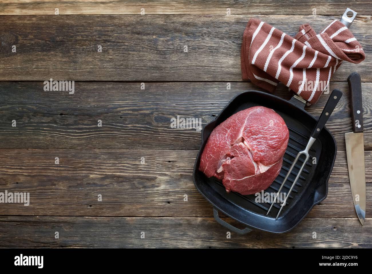 Raw piece of meat for grilling with vegetables in a cast iron pan ...