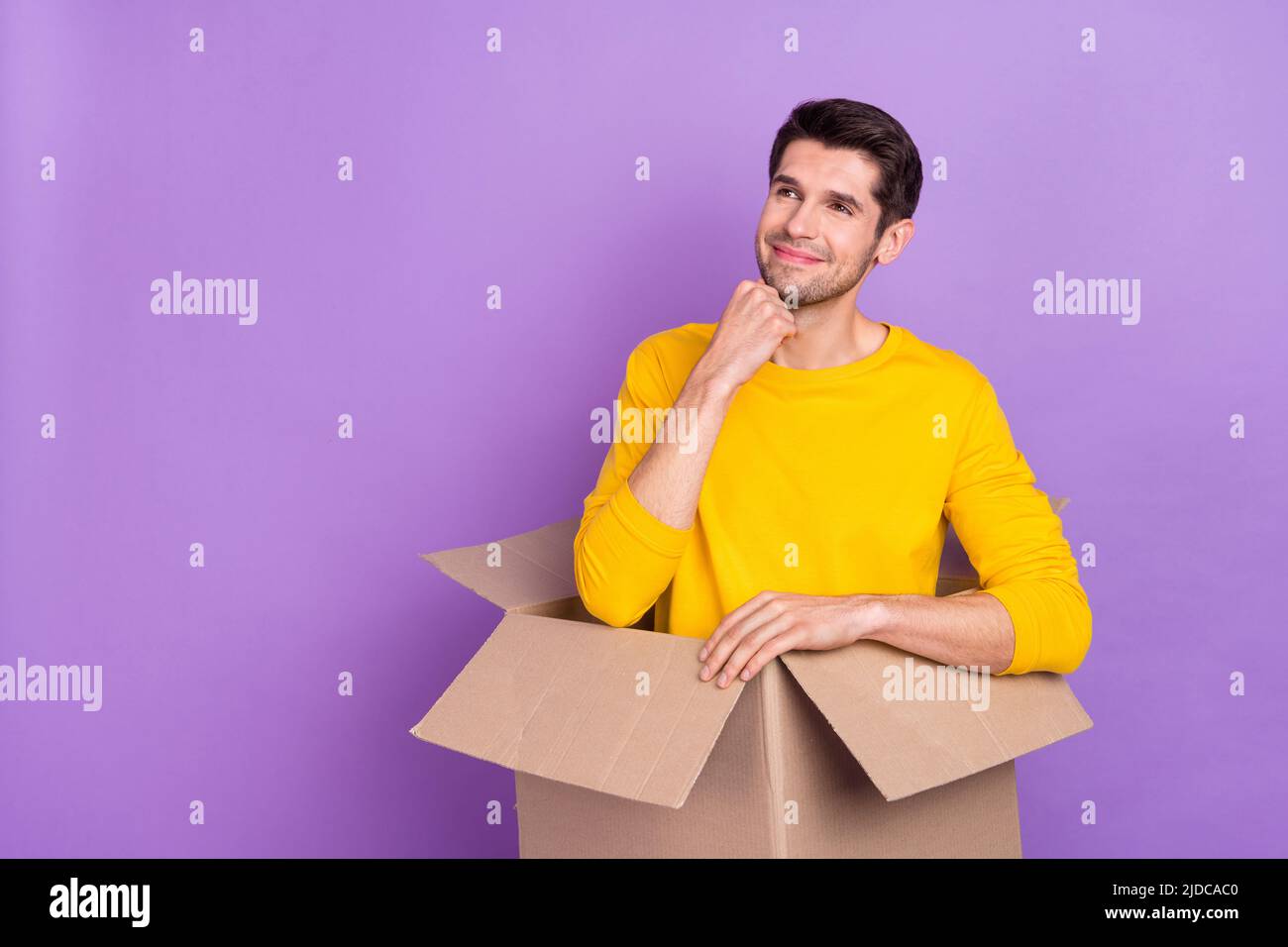 Photo of handsome young homeless man in carton box look empty space ...