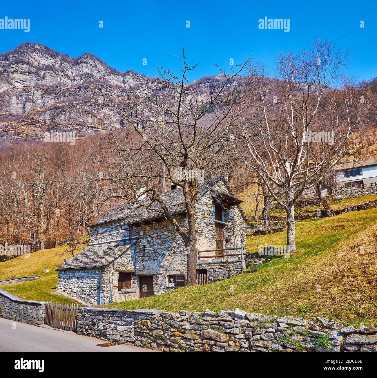 The scenic stone house on the gentle mountain slope, covered with lawn ...