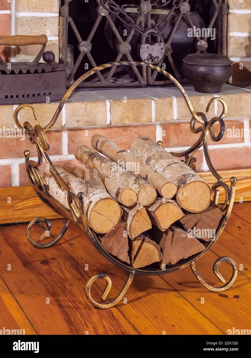 Firewood stack in a bronze basket standing by the fireplace Stock Photo ...
