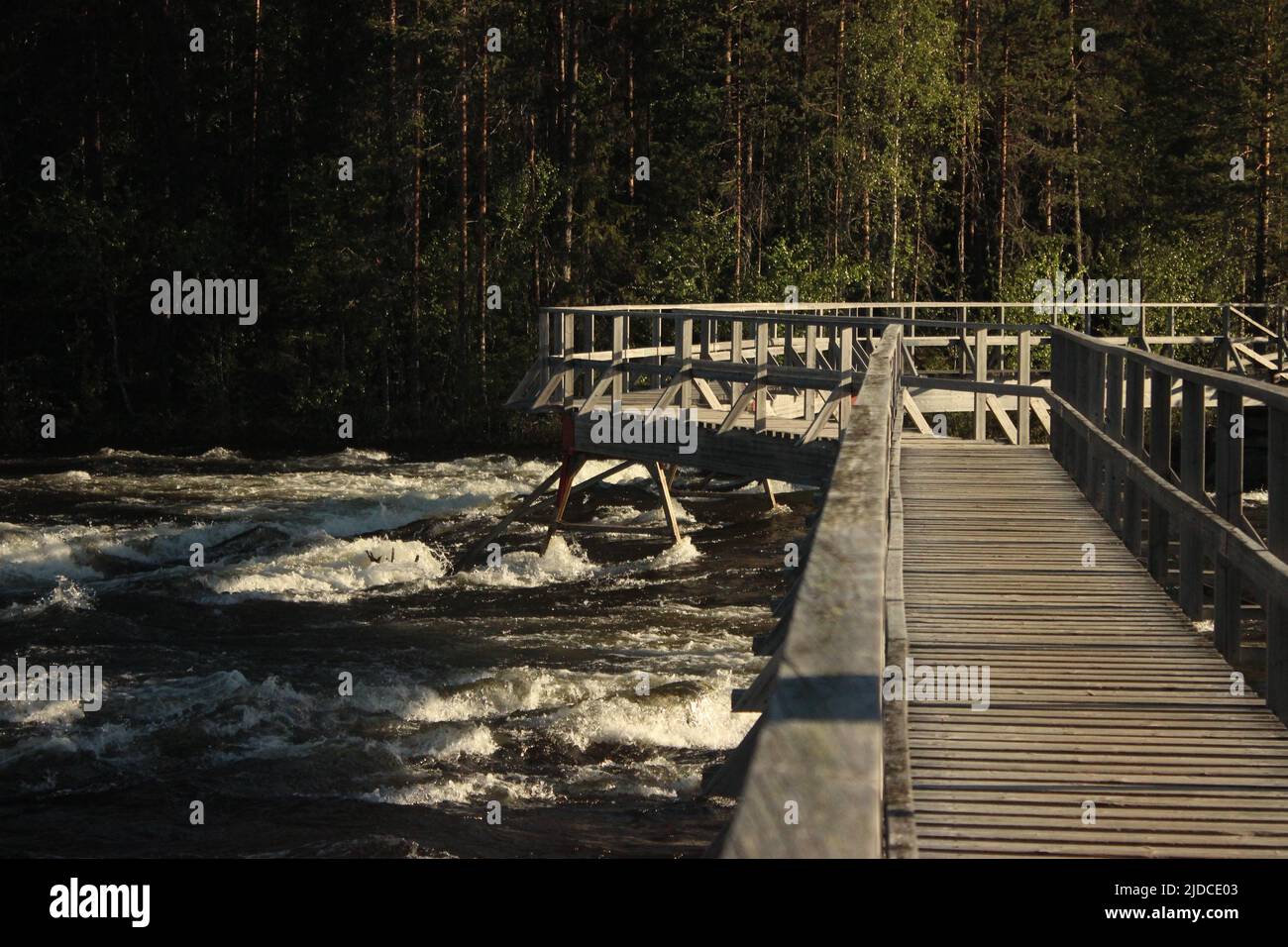 Curved wooden bridge over rapid water Stock Photo - Alamy