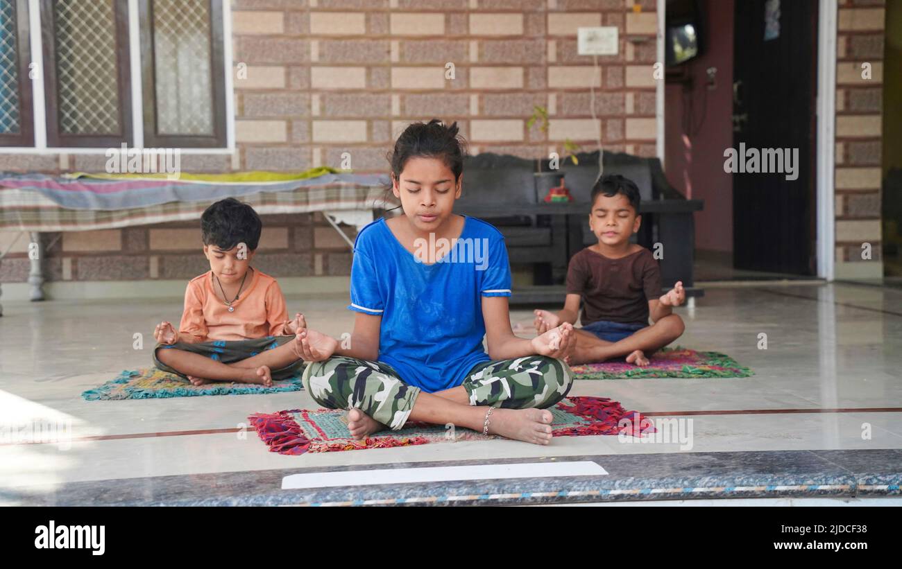 Three Indian little kids doing meditate yoga asana on roll mat with ...