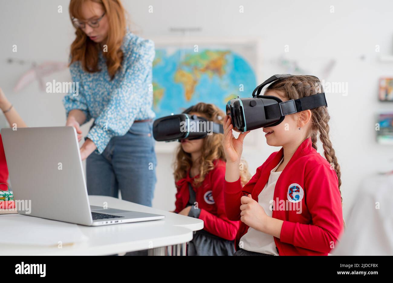 Happy schoolchildren wearing virtual reality goggles at school in ...