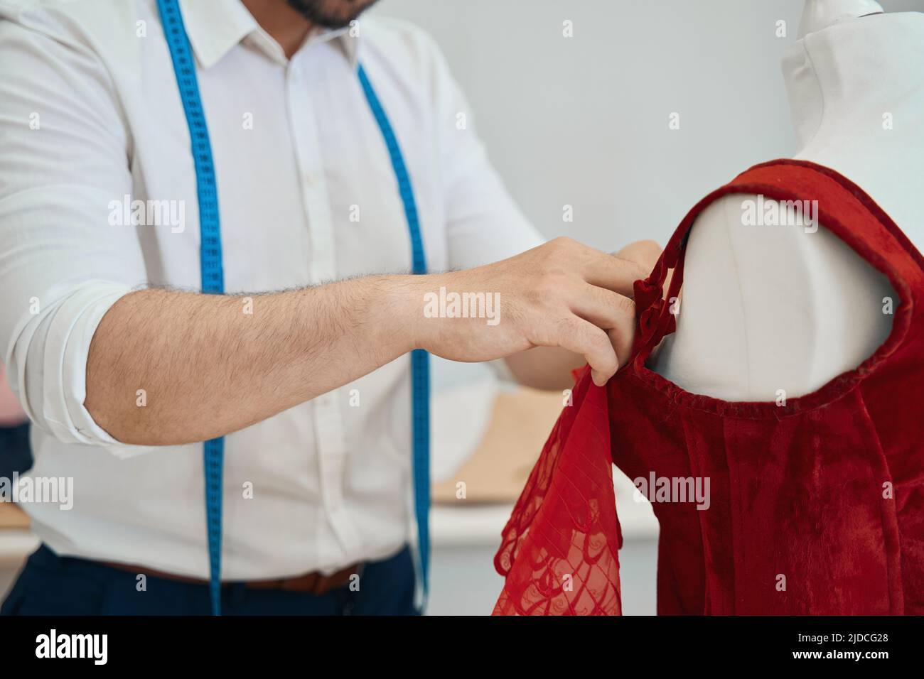 Male tailor with tape sewing lace dress in own atelier Stock Photo - Alamy