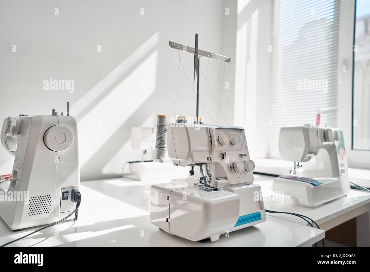 Modern sewing machines on table in factory Stock Photo - Alamy