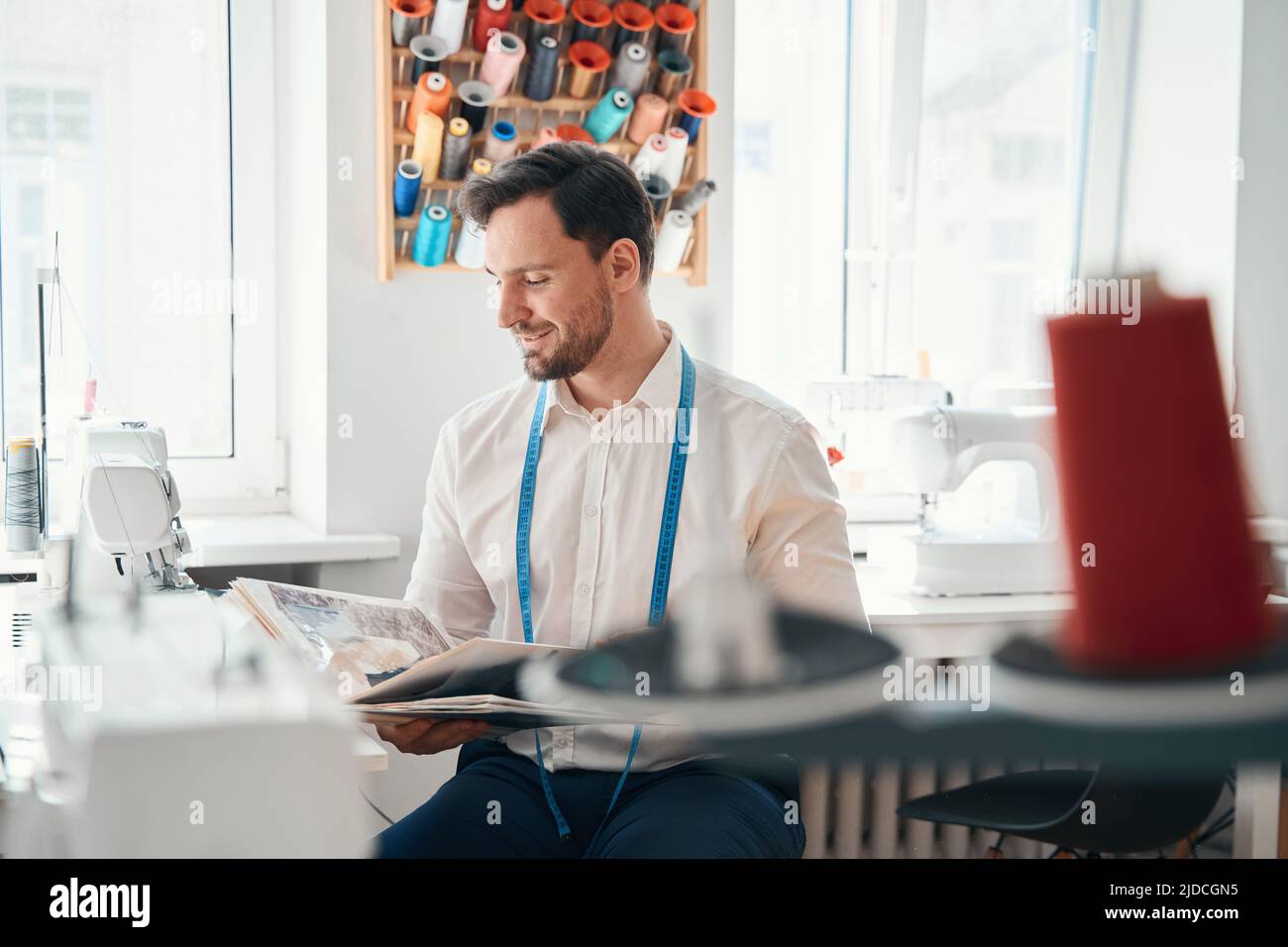 Jolly tailor reading catalog with fabric samples Stock Photo - Alamy