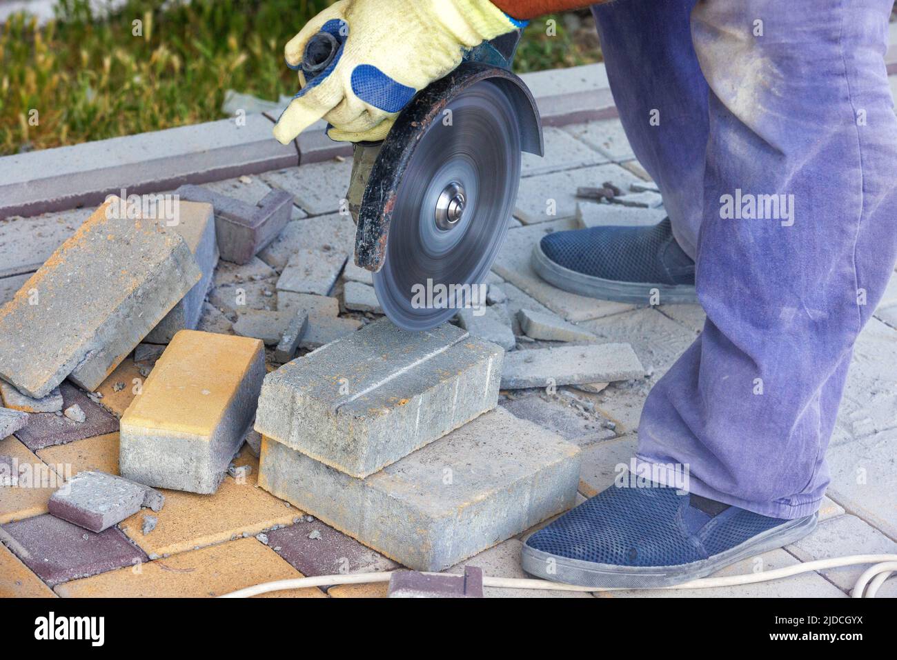 A worker using an electric cutter and a cutting diamond blade cuts ...