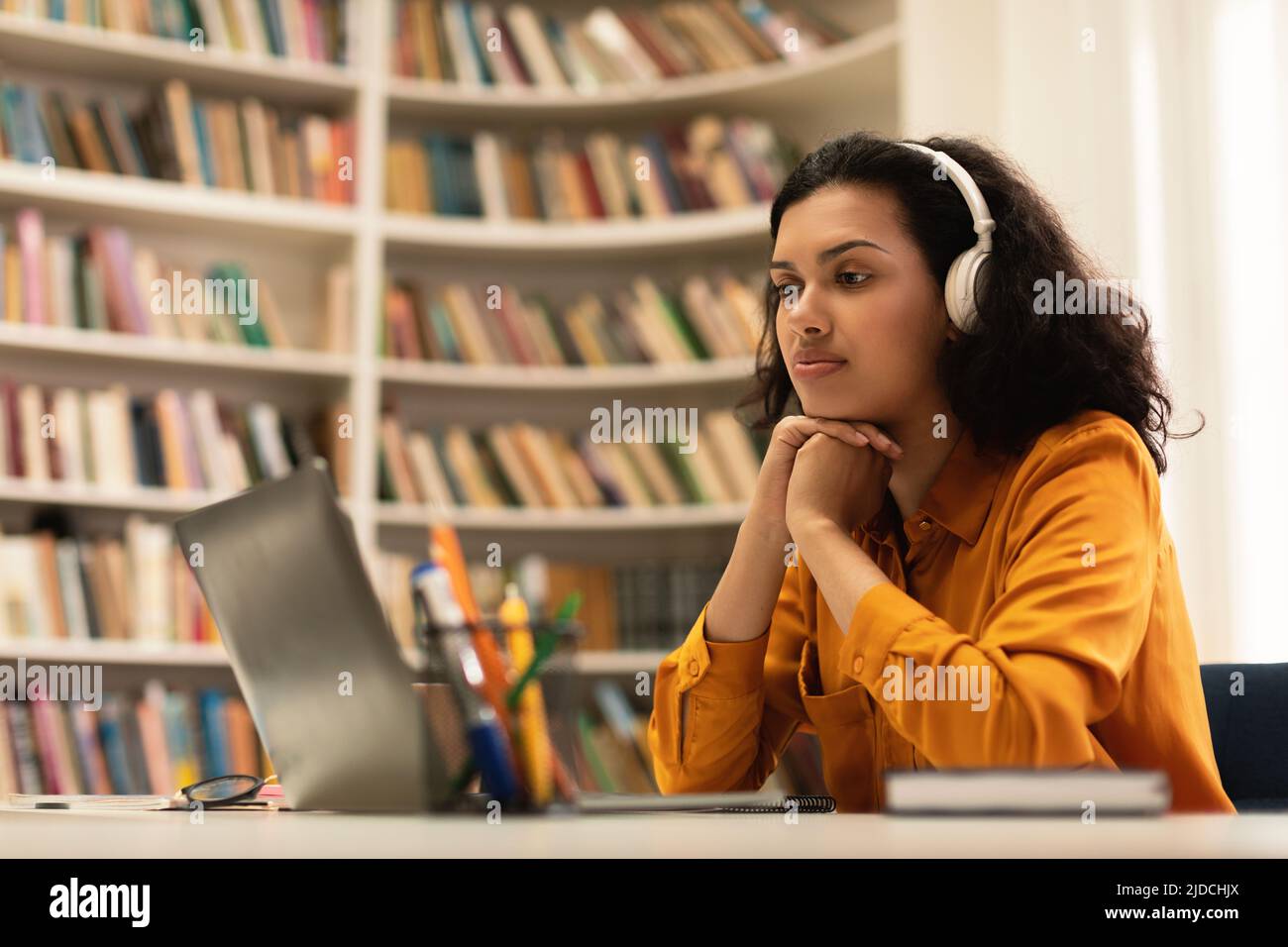 Pensive student lady looking at laptop computer, learning online ...