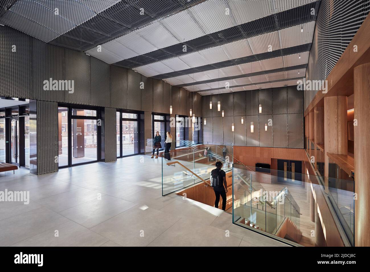 Students in main atrium with wood panelling and metal mesh panel ...