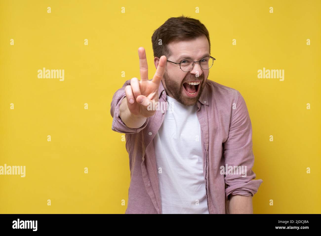 Satisfied man with glasses shows victory symbol, two fingers up sign ...