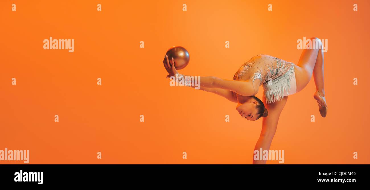 One professional rhythmic gymnastics artist training with golden color ...