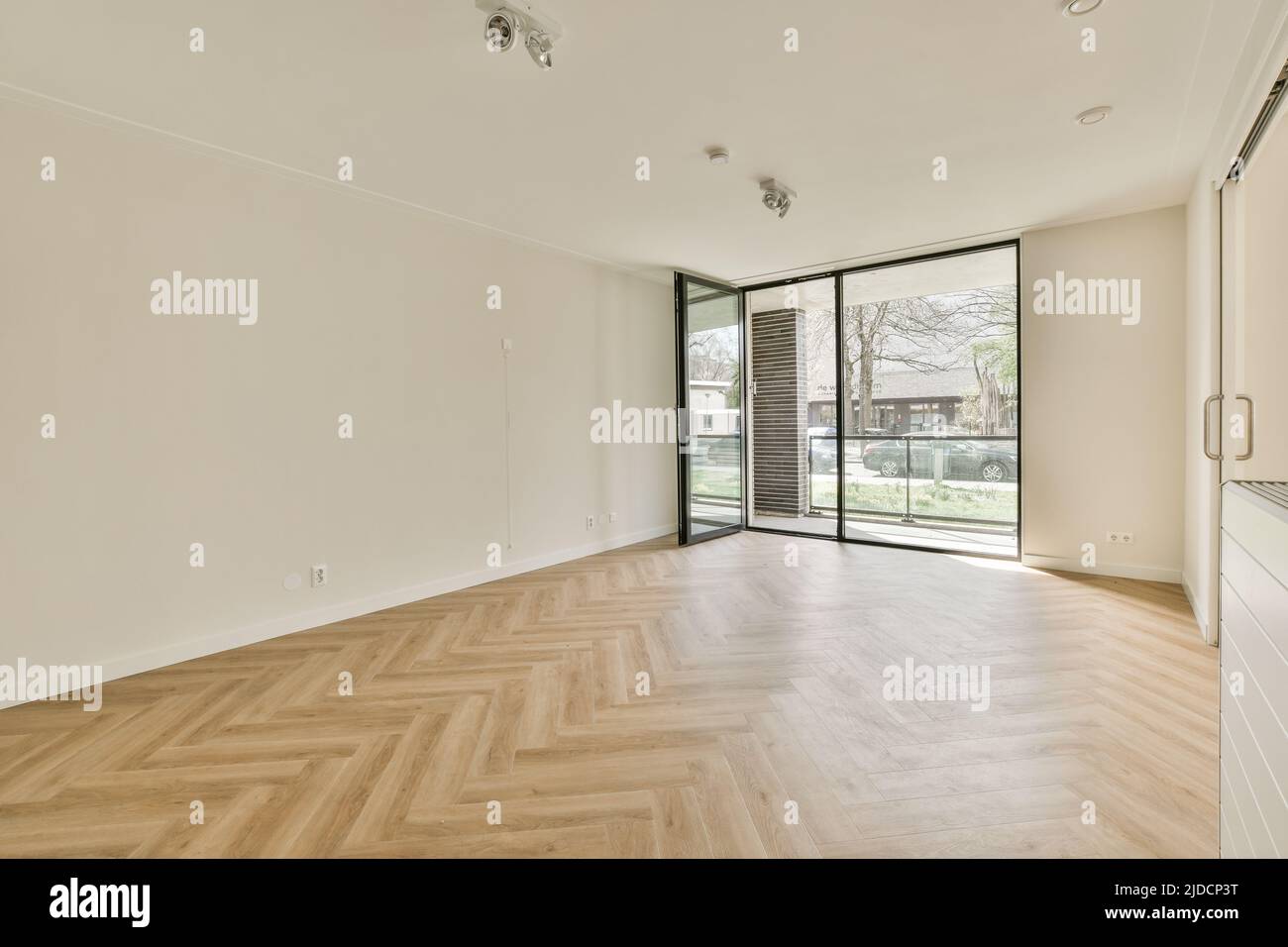 Spacious bright empty room with panoramic windows and parquet floor ...