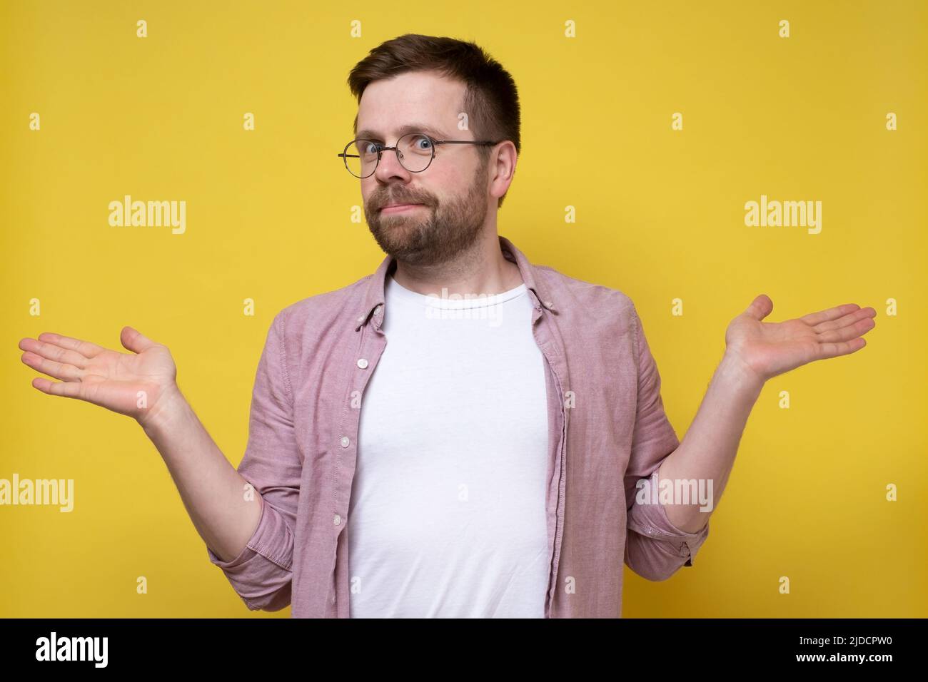 Charming caucasian man in glasses is pleasantly surprised, he spreads ...