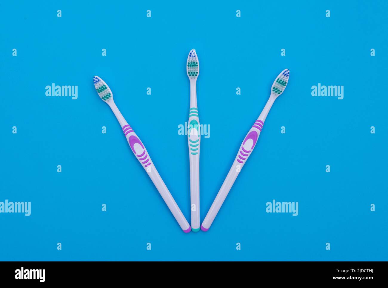three simple toothbrushes for oral hygiene on a light blue background ...