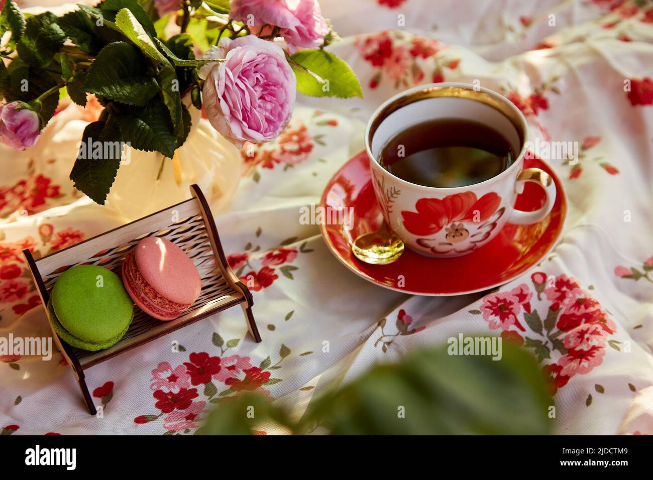 French macarons on the miniature wooden bench in cafe style. Tea rose ...