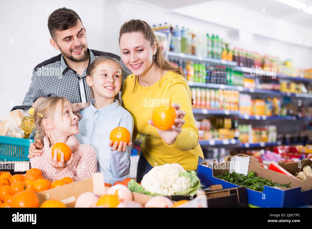 Glad parents with two daughters choosing fruits Stock Photo - Alamy