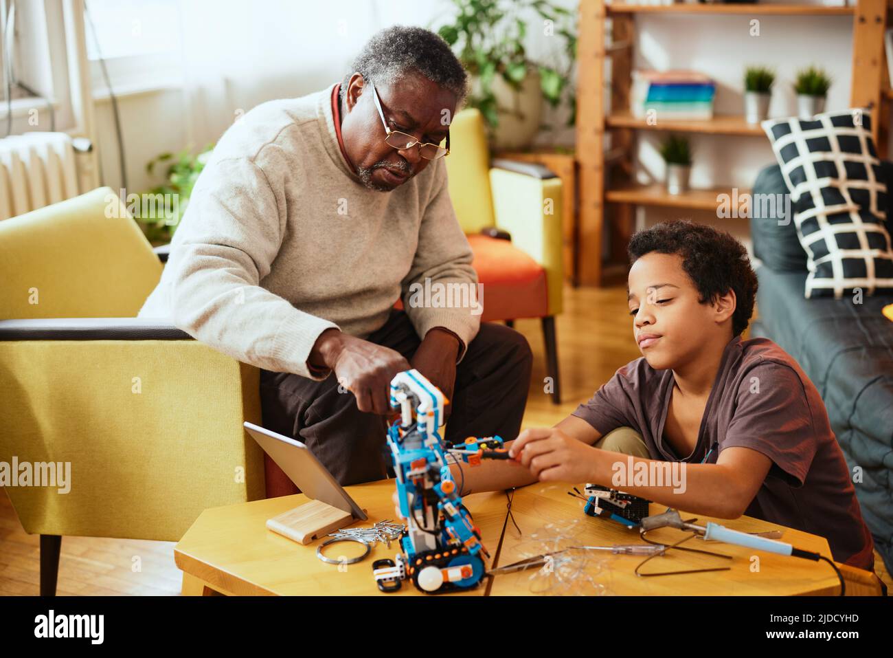 A grandfather showing his grandchild how to make a robot while sitting ...